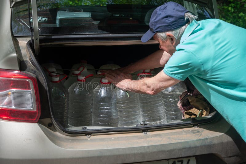 Middle Aged Man Loads Plastic Bottles of Spring Fresh Water into the ...