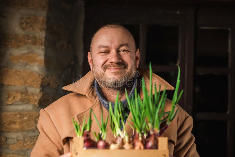 A Middle-aged Man Smiling Looking at the Camera Holds a Growing Green ...