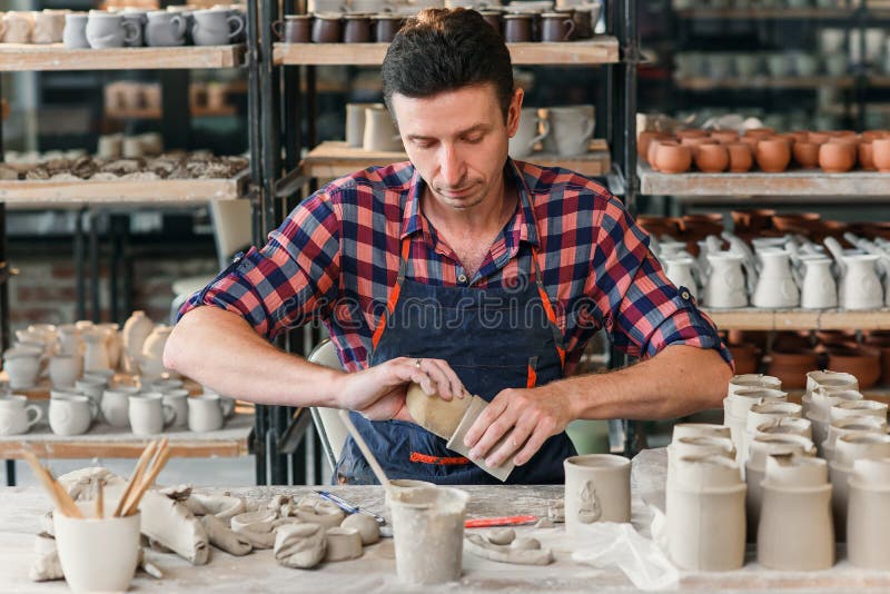 A Middle-aged Man in a Work Uniform Wipes with a Damp Sponge a Clay ...