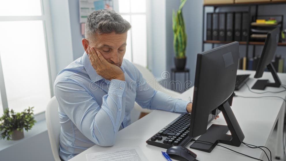 Middle-aged Man Working at a Computer in an Office Looking ...