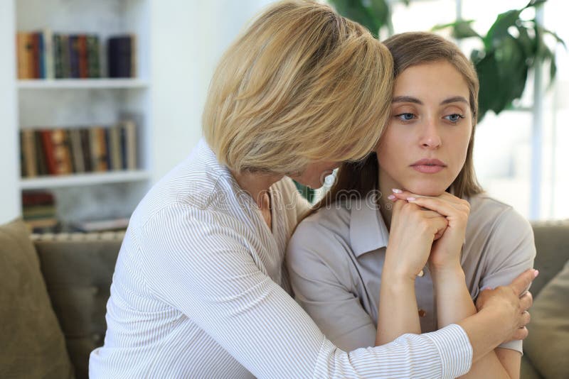 Middle Aged Mother And Daughter Talking On Sofa In Living Room Stock