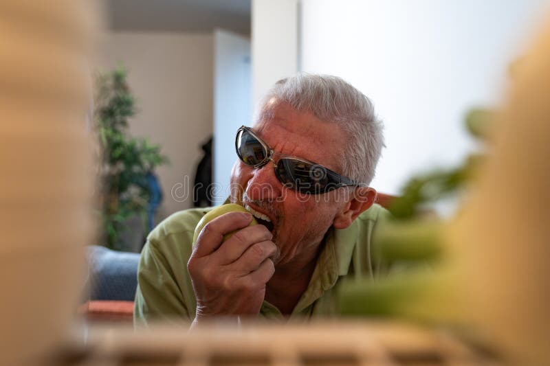 Middle-aged Single Man Biting into an Apple from the Refrigerator ...