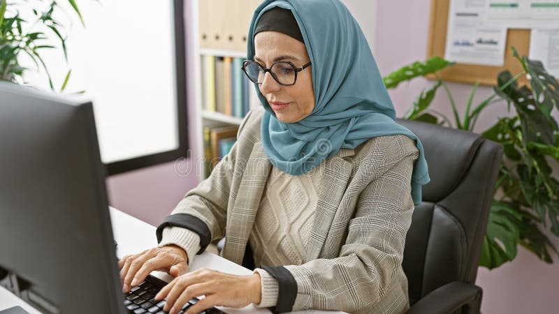 Middle-aged Woman in Hijab Working on Computer in Modern Office Setting ...