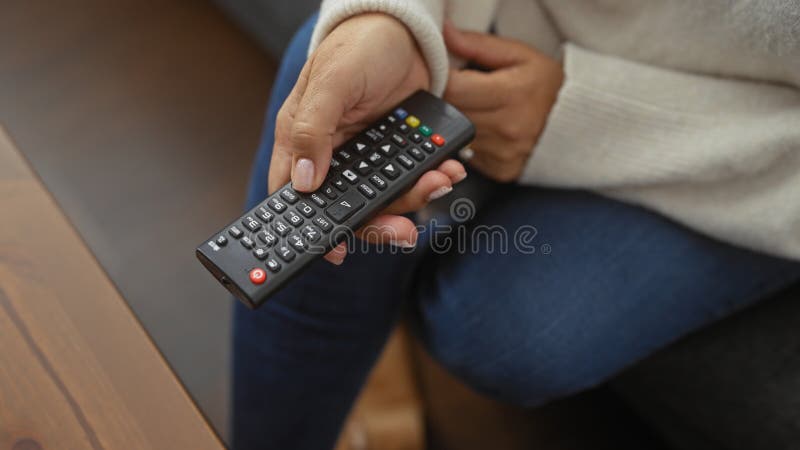 Middle-aged Woman Holding Remote Control, Sitting Indoors in a Casual ...