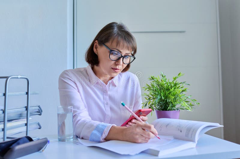 Middle Aged Woman Sitting at Workplace Using Smartphone in Home Office ...