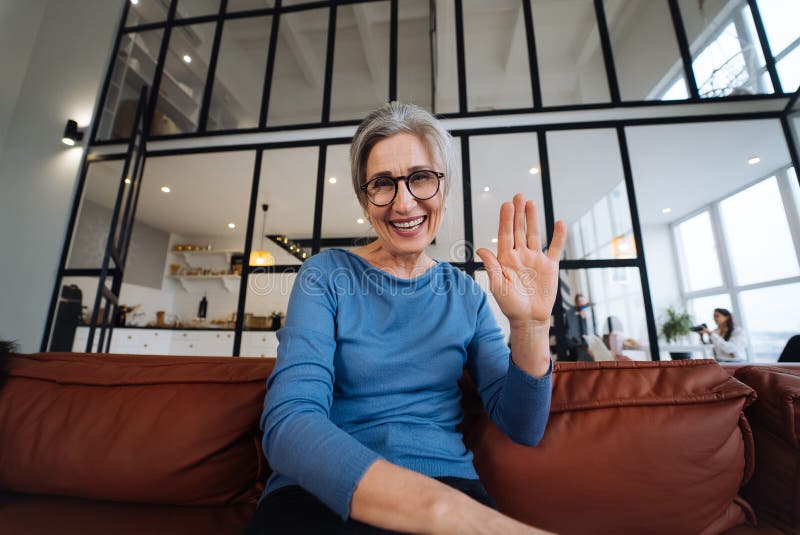 Middle Aged Woman Smiles and Waves To the Camera, Looking at Camera ...