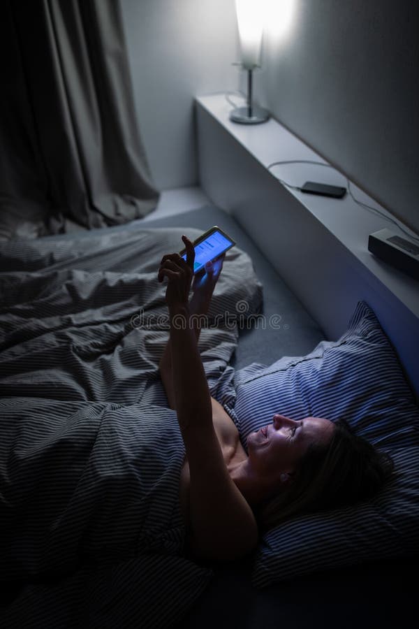 Middle-aged Woman Using Her Tablet Computer before Sleep in Bed in the ...