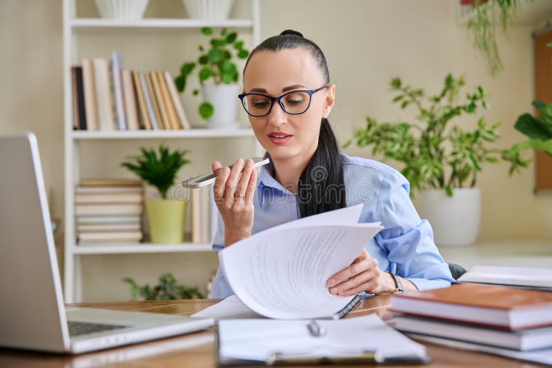 Middle Aged Woman Working with Computer, Using Smartphone, in Home ...