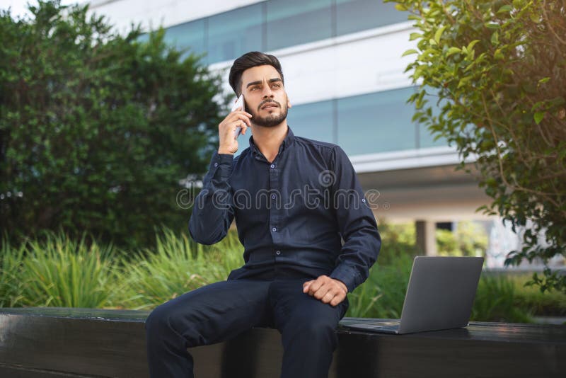 Middle Eastern Business Man Communicating Via Phone with Laptop Outside ...