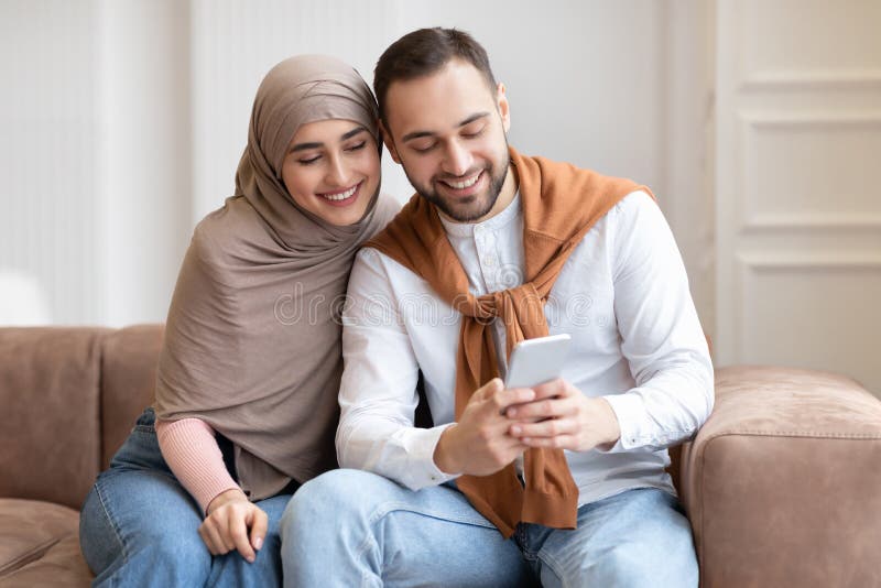 Middle Eastern Spouses Browsing Internet on Smartphone Indoors Stock ...