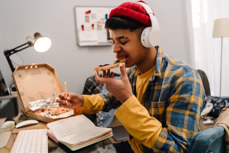 Middle-eastern Teenage Boy Eating Pizza Studying at Home by Computer ...