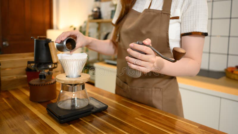 Midsection of Young Woman in Apron Pouring Ground Coffee into a Dripper ...