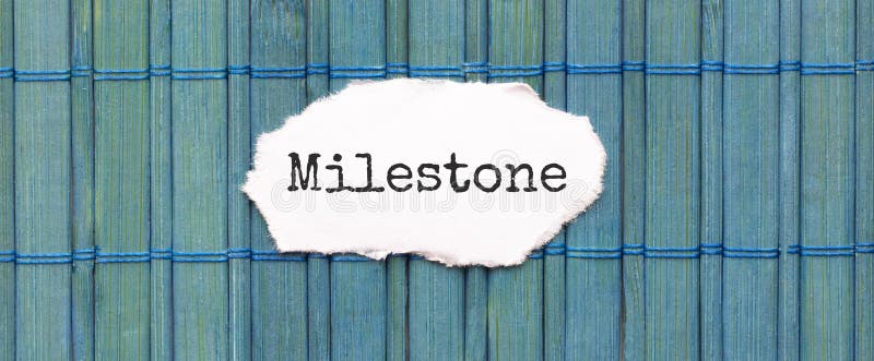 MILESTONE Text on the Piece of Paper on the Green Wood Background Stock ...