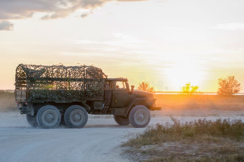 A Military Car is Driving Along the Sandy Road at Sunset Stock Image ...
