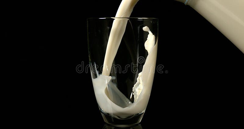 Milk Being Poured into Glass Against Black Background Stock Photo ...