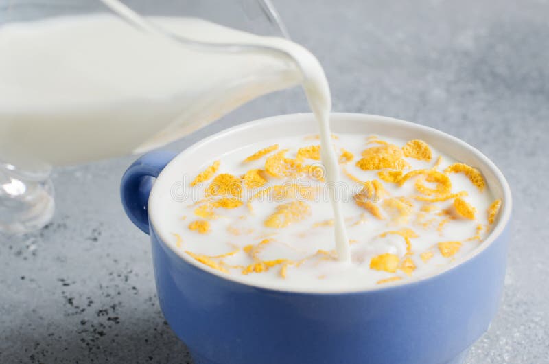 Milk is Poured into Corn Flakes. Blue Cup on a Concrete Background ...