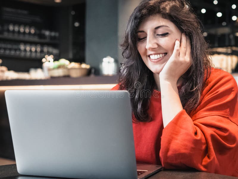 Millennial Girl Smiles while Working on the Pc in a Cafe - Remote ...
