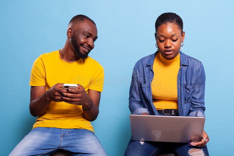 Millennials Couple Using Smartphone and Laptop in Studio Stock Photo ...