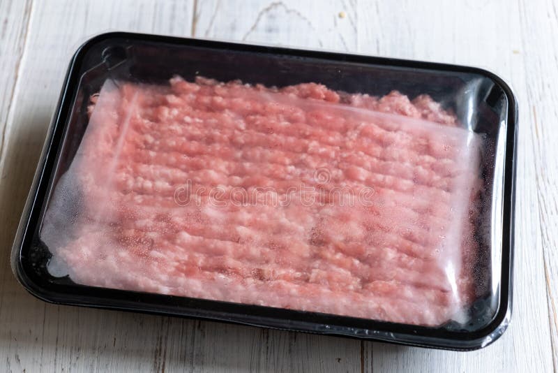 Minced Meat in Plastic Packaging on a Light Wooden Background Stock ...