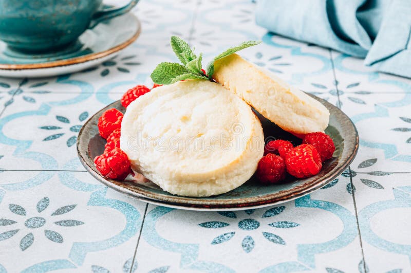 Mini Cheesecakes with Fresh Raspberry on Blue Plate Over Tiled ...