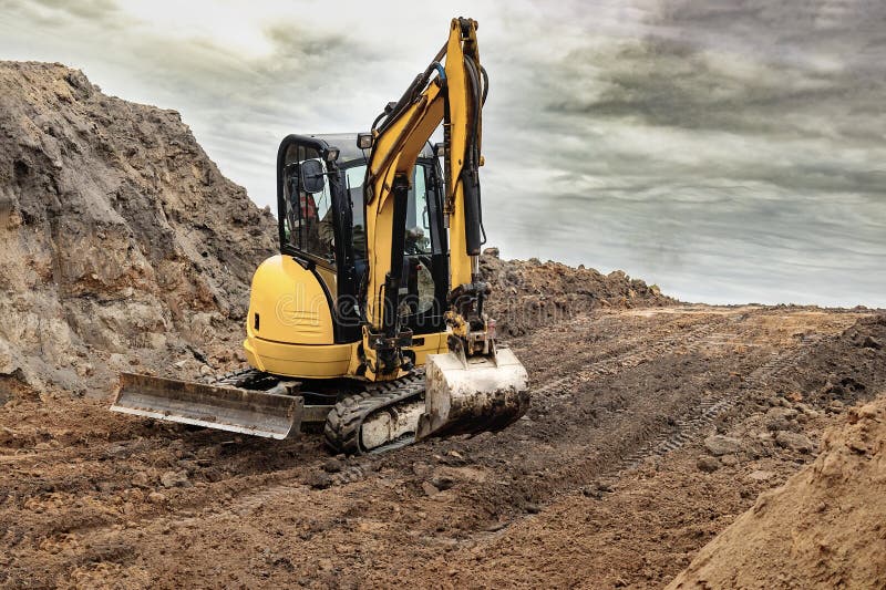 Mini Excavator at the Construction Site on the Edge of a Pit Against a ...