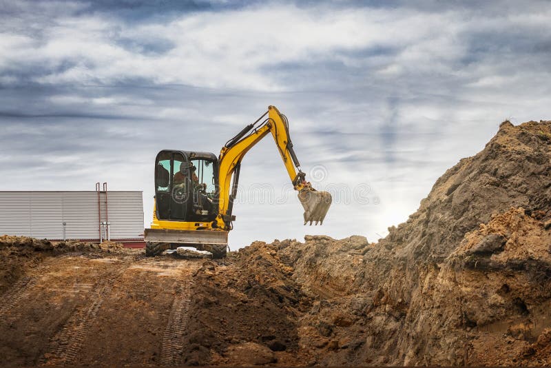 Mini Excavator at the Construction Site on the Edge of a Pit Against a ...