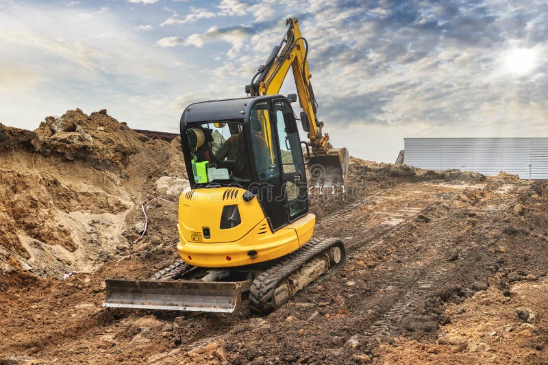 Mini Excavator at the Construction Site on the Edge of a Pit Against a ...