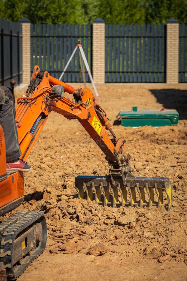 A Mini Excavator with a Rake Loosens the Ground. Landscape Preparation ...