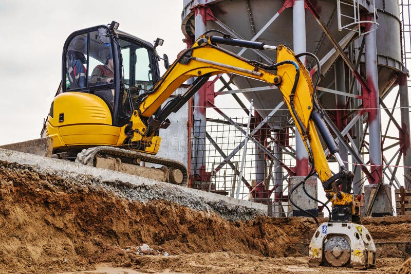 A Mini Excavator Rams the Ground with a Vibrating Plate. Laying of ...