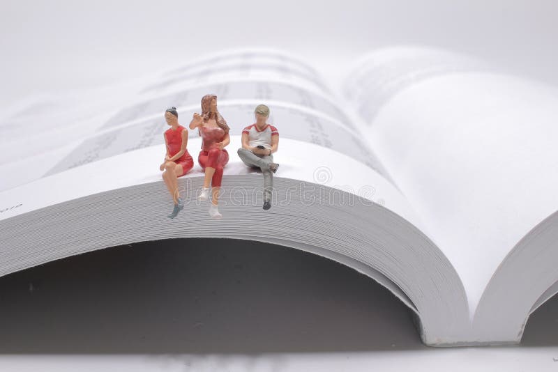 Mini Figure Reading Newspaper and Sitting on Book Stock Image - Image ...