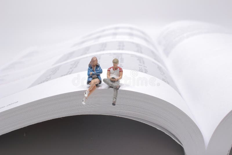 Mini Figure Reading Newspaper and Sitting on Book Stock Image - Image ...