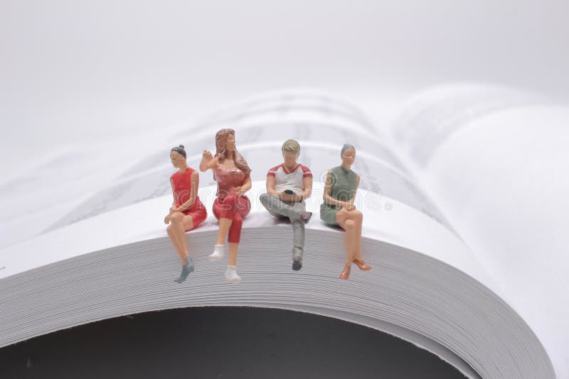 Mini Figure Reading Newspaper and Sitting on Book Stock Photo - Image ...