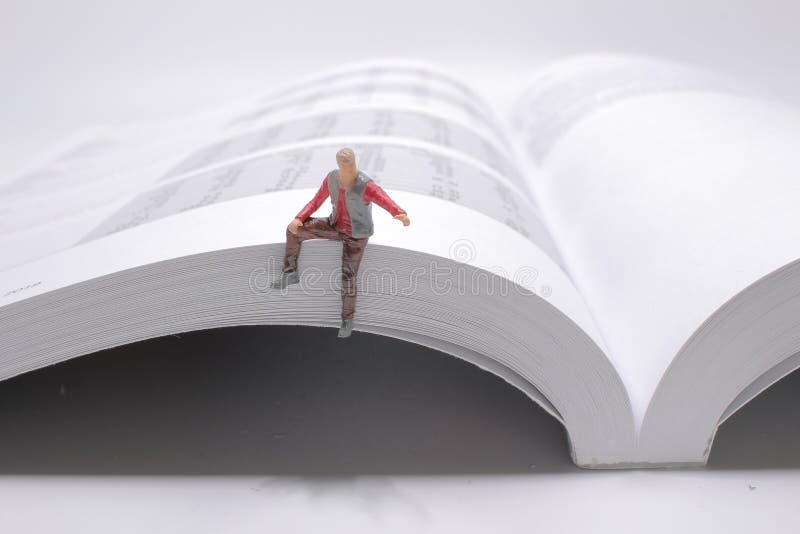 Mini Figure Reading Newspaper and Sitting on Book Stock Image - Image ...
