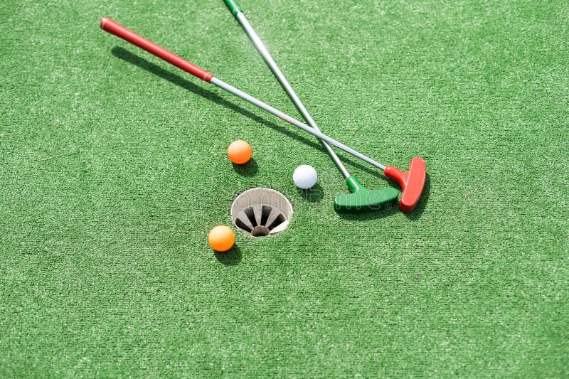 Mini-golf Clubs and Balls of Different Colors Laid on Artificial Grass ...