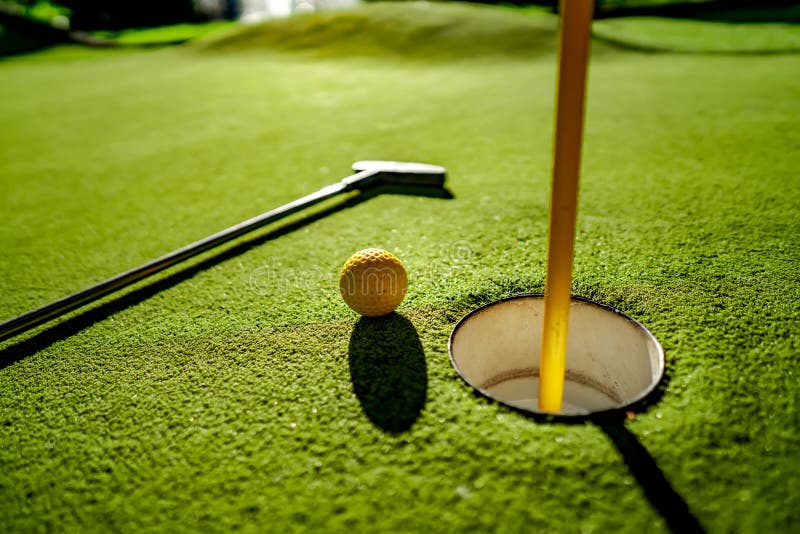 Mini Golf Yellow Ball with a Bat Near the Hole at Sunset Stock Photo ...