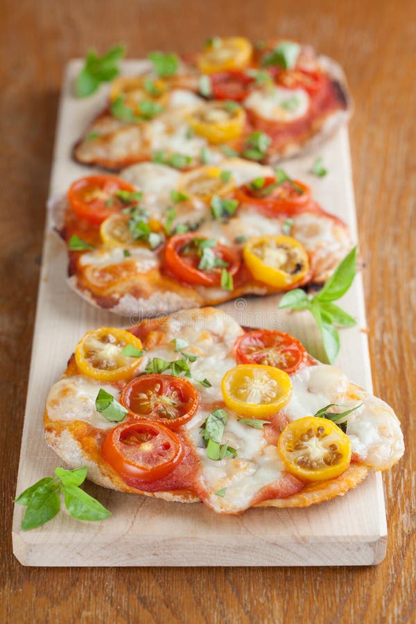 Mini Pizzas with Mozzarella, Cherry Tomatoes and Basil Stock Photo ...