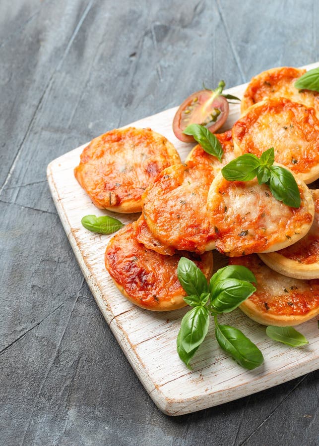 Mini Pizzas with Tomatoes and Mozzarella Cheese on White Wooden Board ...