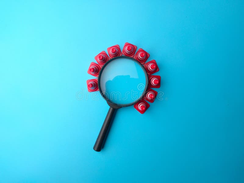 Mini Plastic Cones and Magnifying Glass on a Blue Background Stock ...