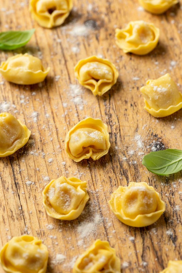 Mini Raw Ravioli with Flour and Basil on Wooden Board Stock Photo ...