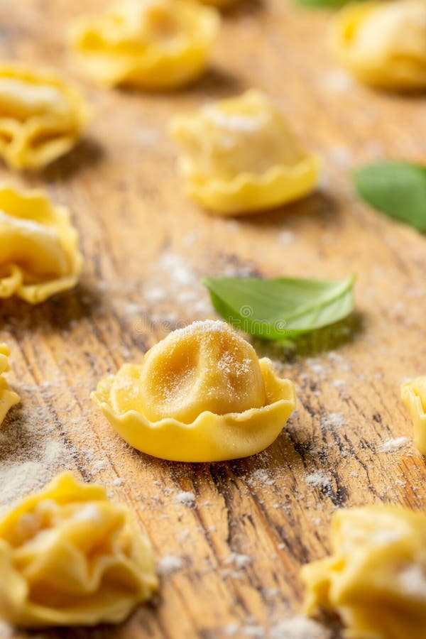 Mini Raw Ravioli with Flour and Basil on Wooden Board Stock Photo ...