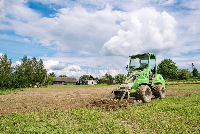 Mini Skid Steer Loader Clear a Construction Site. Small Tractor with a Ground Leveler Moves Soil ...