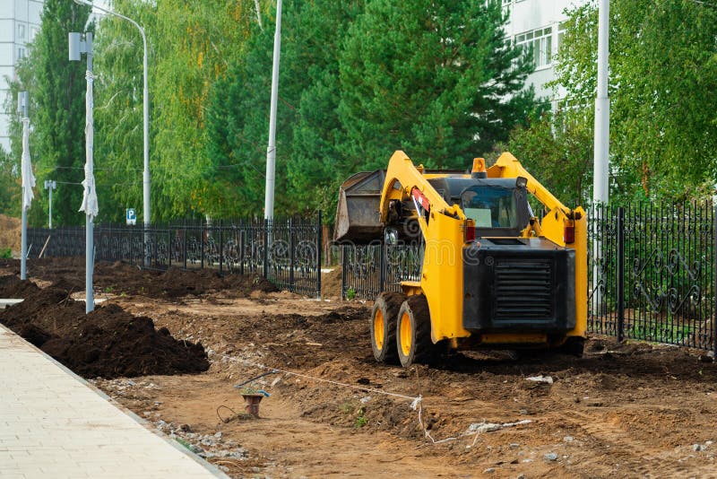 Mini Tractor with a Bucket at Work on a Construction Site. Small Yellow ...