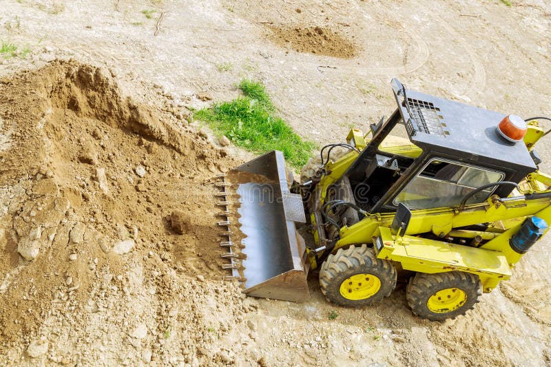 A Mini Tractor-loader Moves and Loads Earth on a Construction Site ...