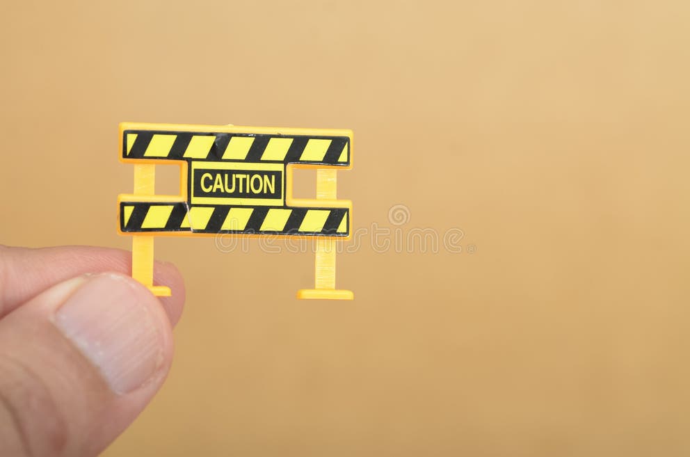 Miniature Caution Barricade Held between Fingers Symbolizing Warning ...