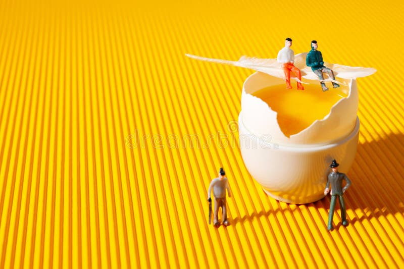 Miniature People and Egg on Textured Yellow Background Stock Image ...