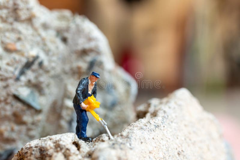 A Miniature Worker Worker Drilling a Big Rock . Themes of Perseverance ...
