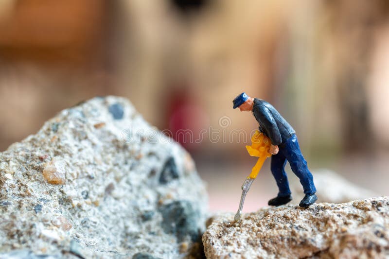 A Miniature Worker Worker Drilling a Big Rock . Themes of Perseverance ...