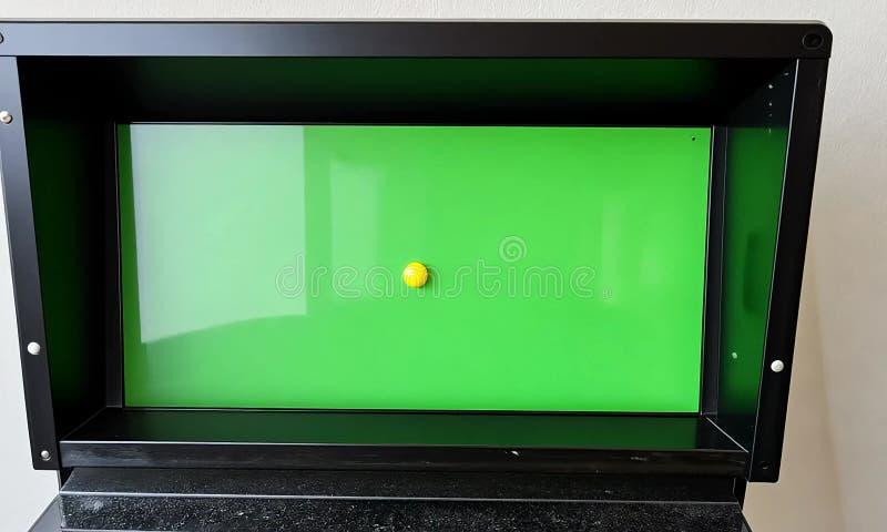 A Minimalist Arcade Game Setup Featuring a Yellow Ball on a Green ...