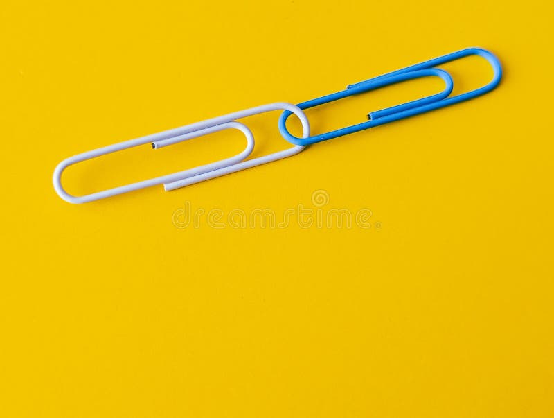 Two Paper Clips Linked Together on Bright Yellow Background Stock Image ...