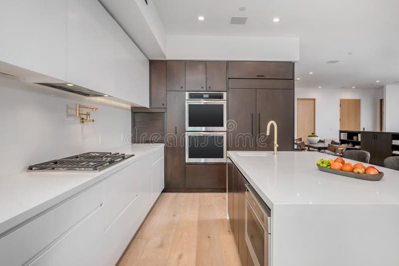 An Empty White Kitchen with a Center Island Next To a Table and Two ...